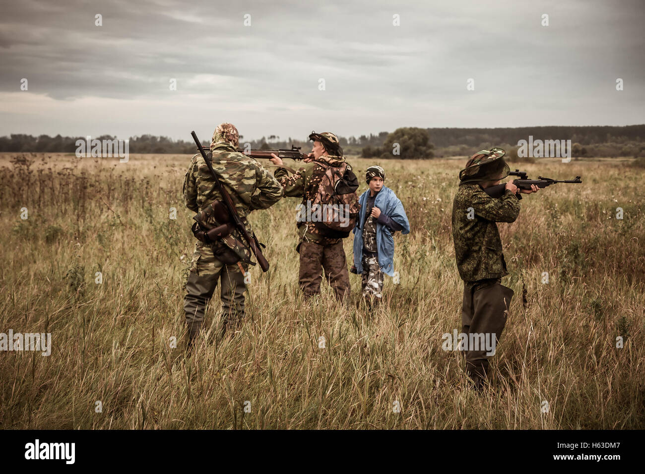 Hunting scene with hunters aiming during hunting season in rural field ...