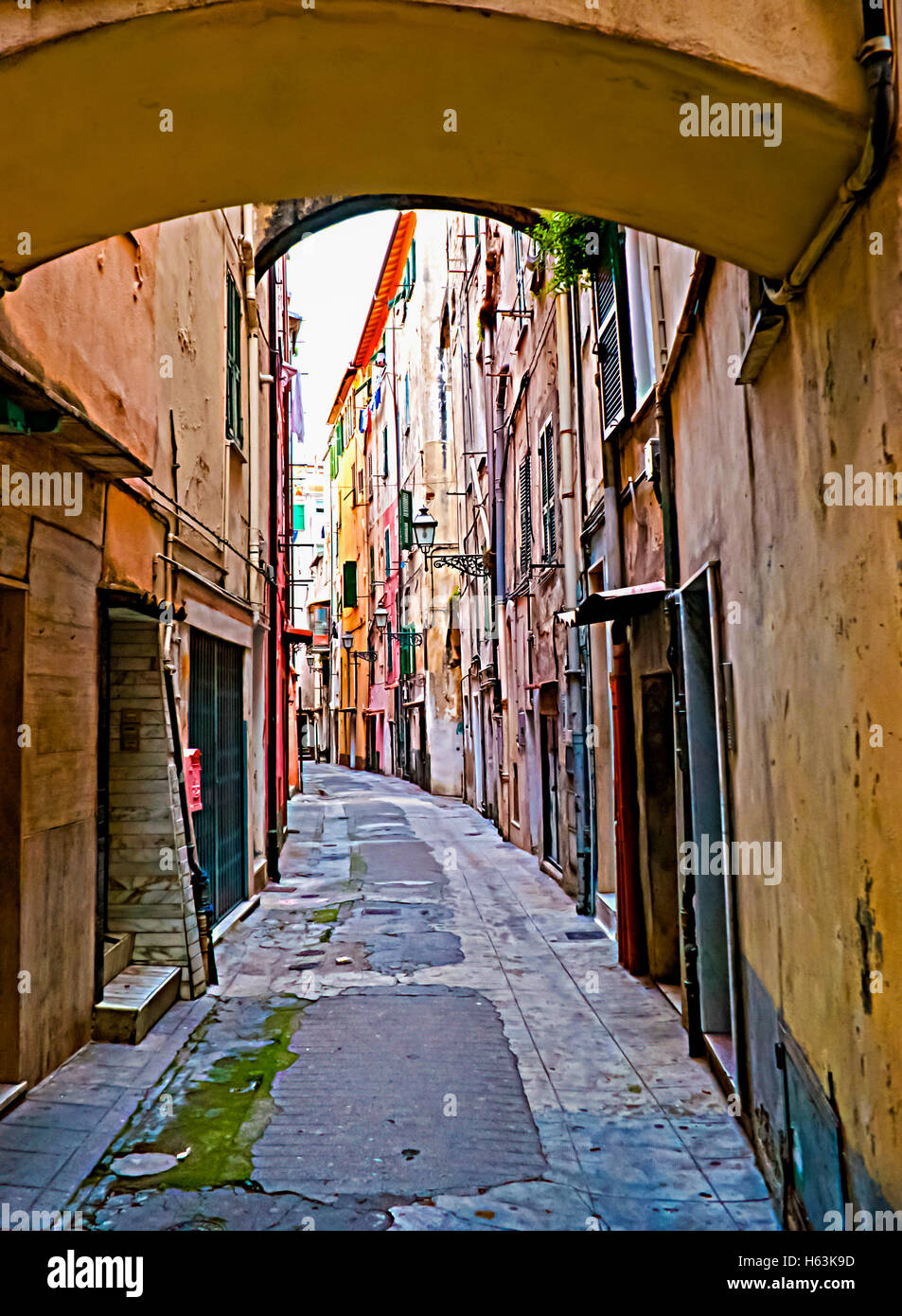 The narrow shabby street with an old arch and tall townhouses in ...