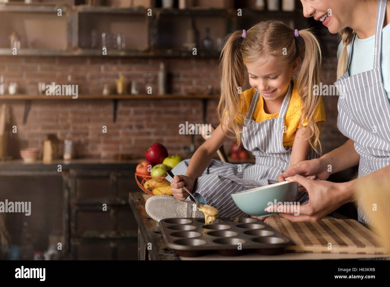 Smiling involved girl helping her mother cooking pastry Stock Photo - Alamy