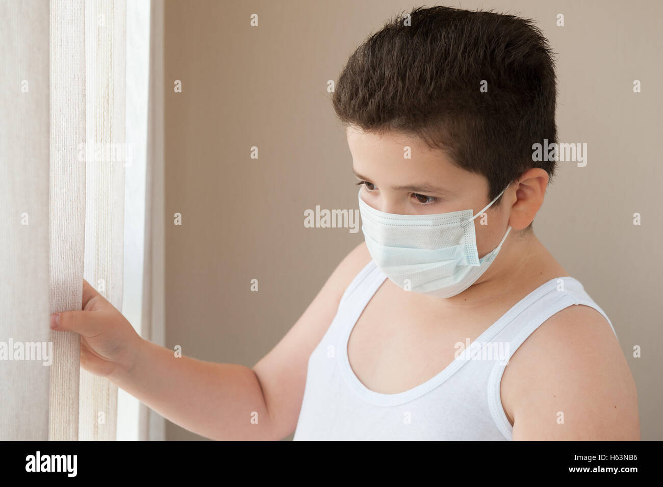fat boy wearing a shirt and a surgical mask looking out the window in ...