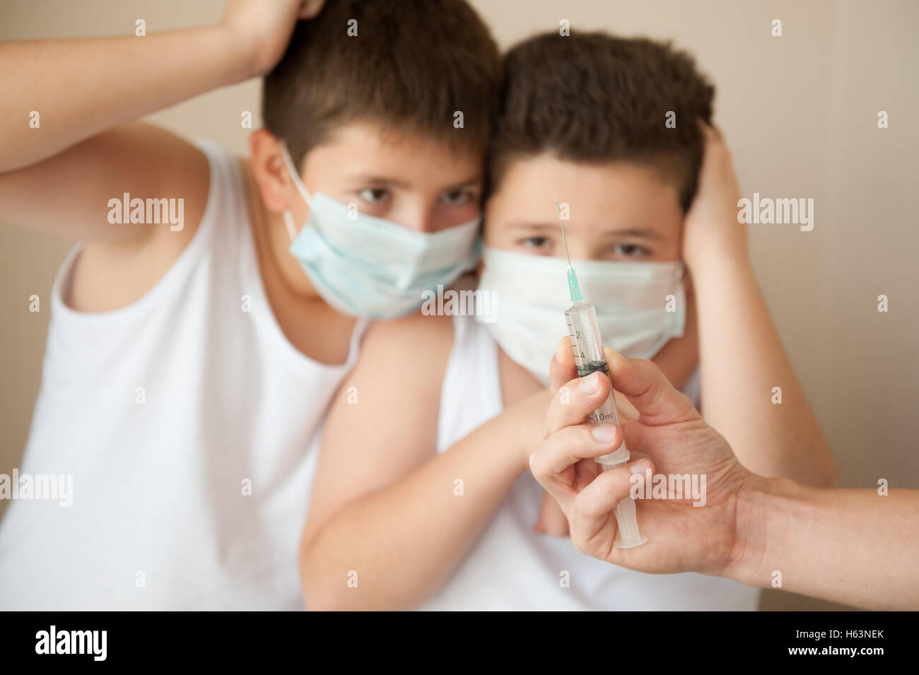 two scared boys in a medical mask looking at hand with syringe Stock ...