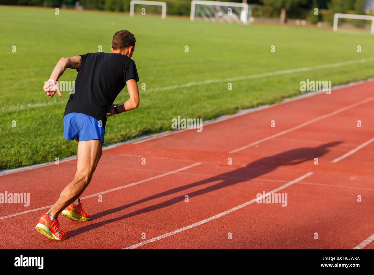 Portrait in full growth of running man on track outdoors on summer ...