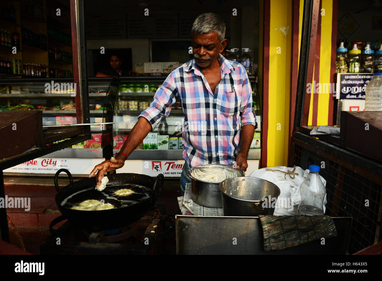 A cook preparing Medu Vada in a street food stall in Tamil Nadu, India ...