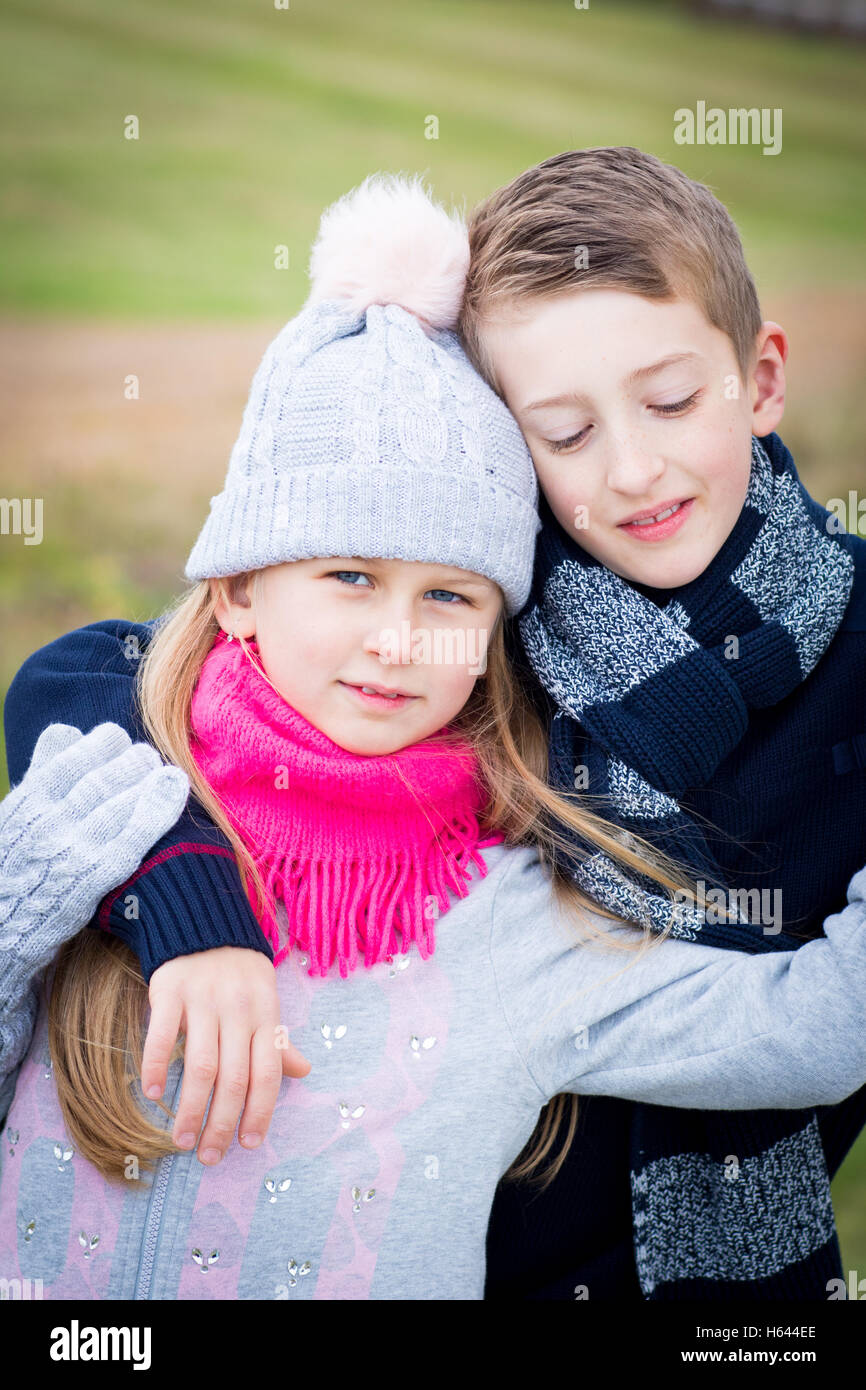 Brother and sister posing outdoors in autumn wearing worm clothes and ...