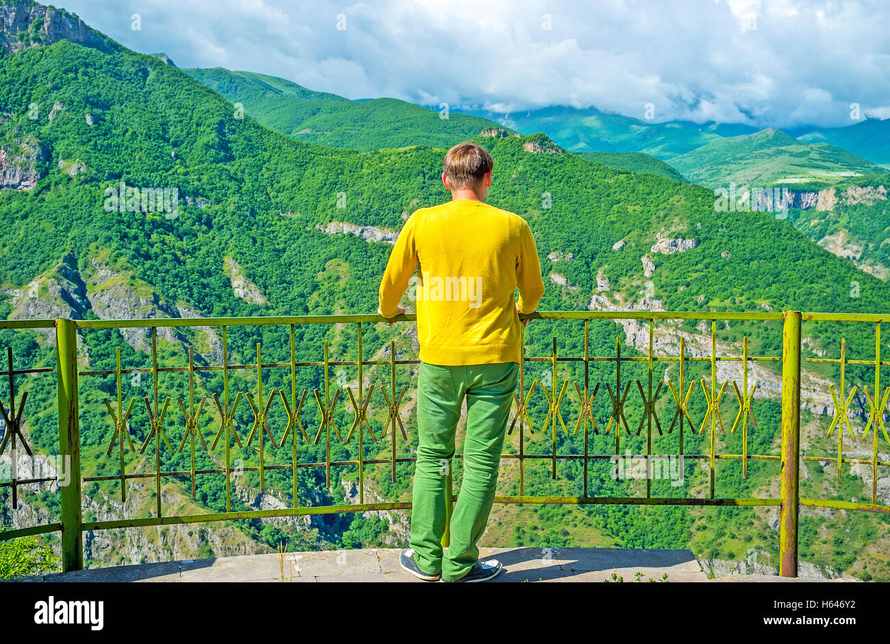 The man stands on the cliff's edge and enjoys the view of Vorotan river ...
