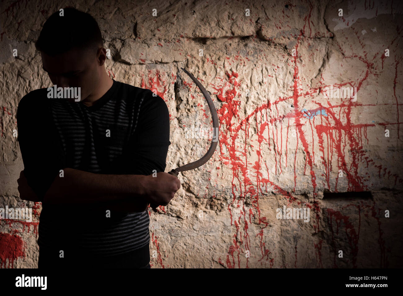 Man holding a sickle standing near blood stained wall for concept about ...