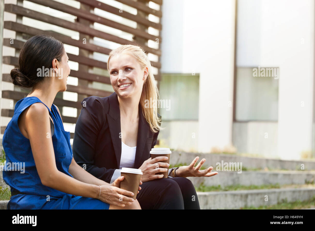Two businesswomen talking outside during a coffee break Stock Photo - Alamy