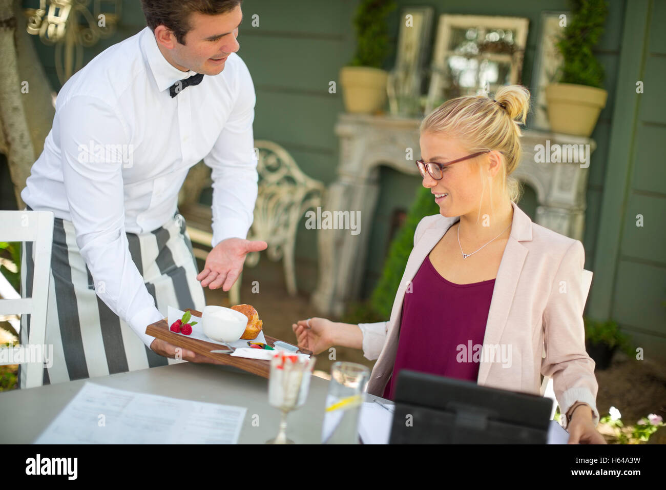 Waiter serving dessert to businesswoman at outdoor restaraunt Stock ...