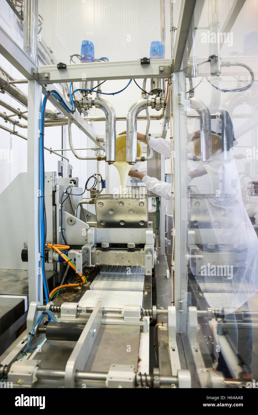 Woman pouring liquid white chocolate in a machine in a chocolate ...