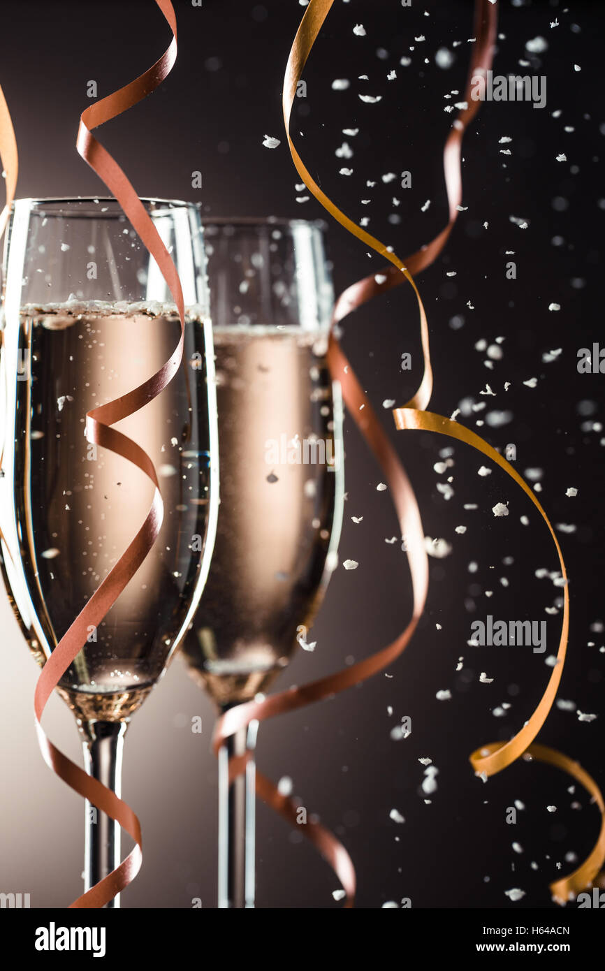Two champagne glasses, decorative ribbon on dark background with ...