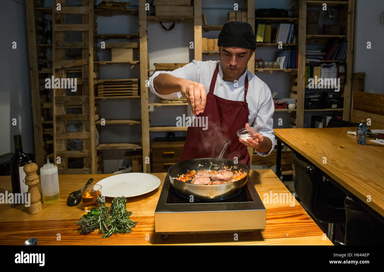Man pouring salt on beef cheeks in a pan with sauteed vegetables Stock ...