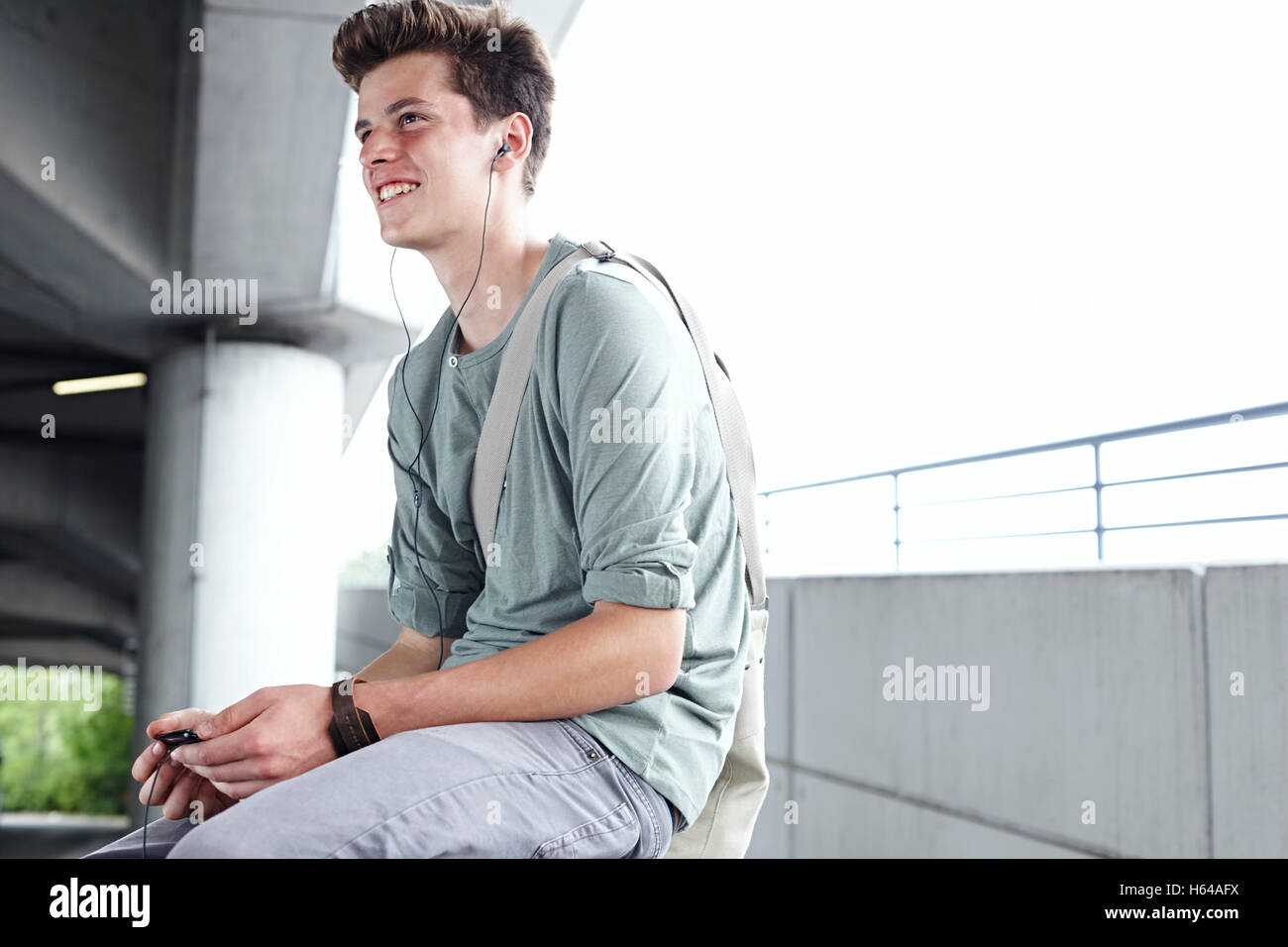 Smiling teenage boy with cell phone and earbuds outdoors Stock Photo ...
