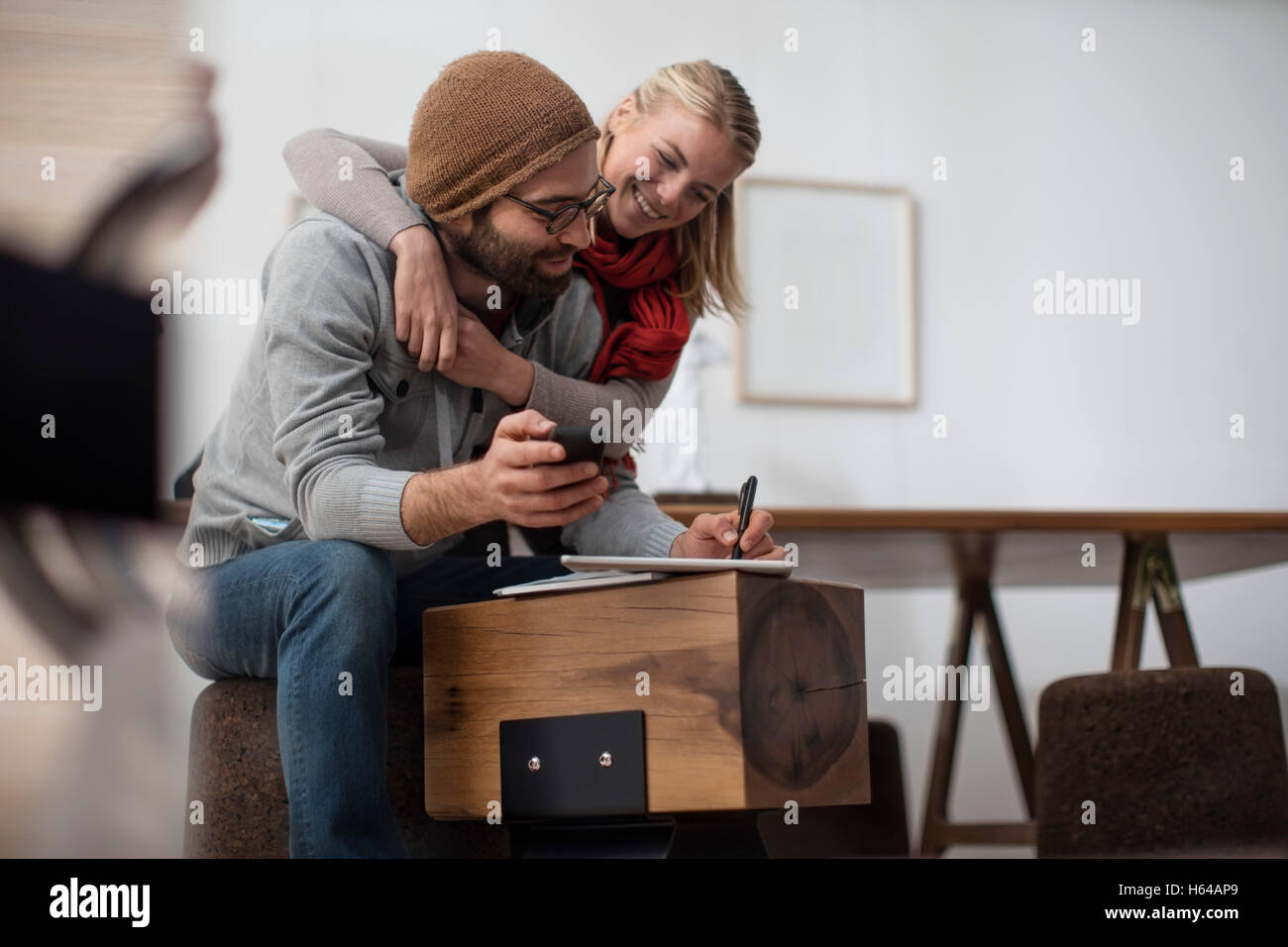 Young couple embracing one another while working in designer office ...