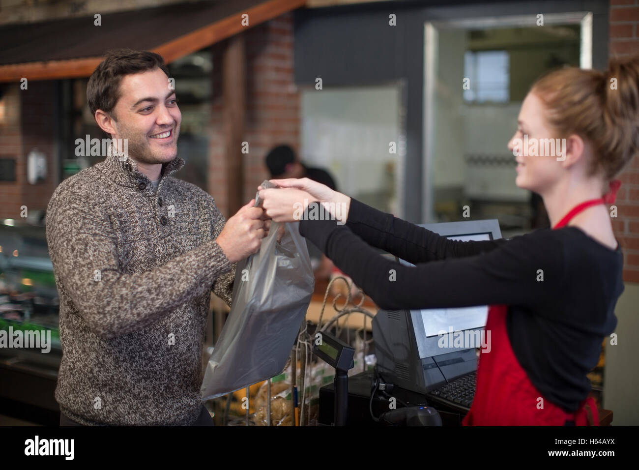 Shop assistant handing over bag to customer in shop Stock Photo - Alamy