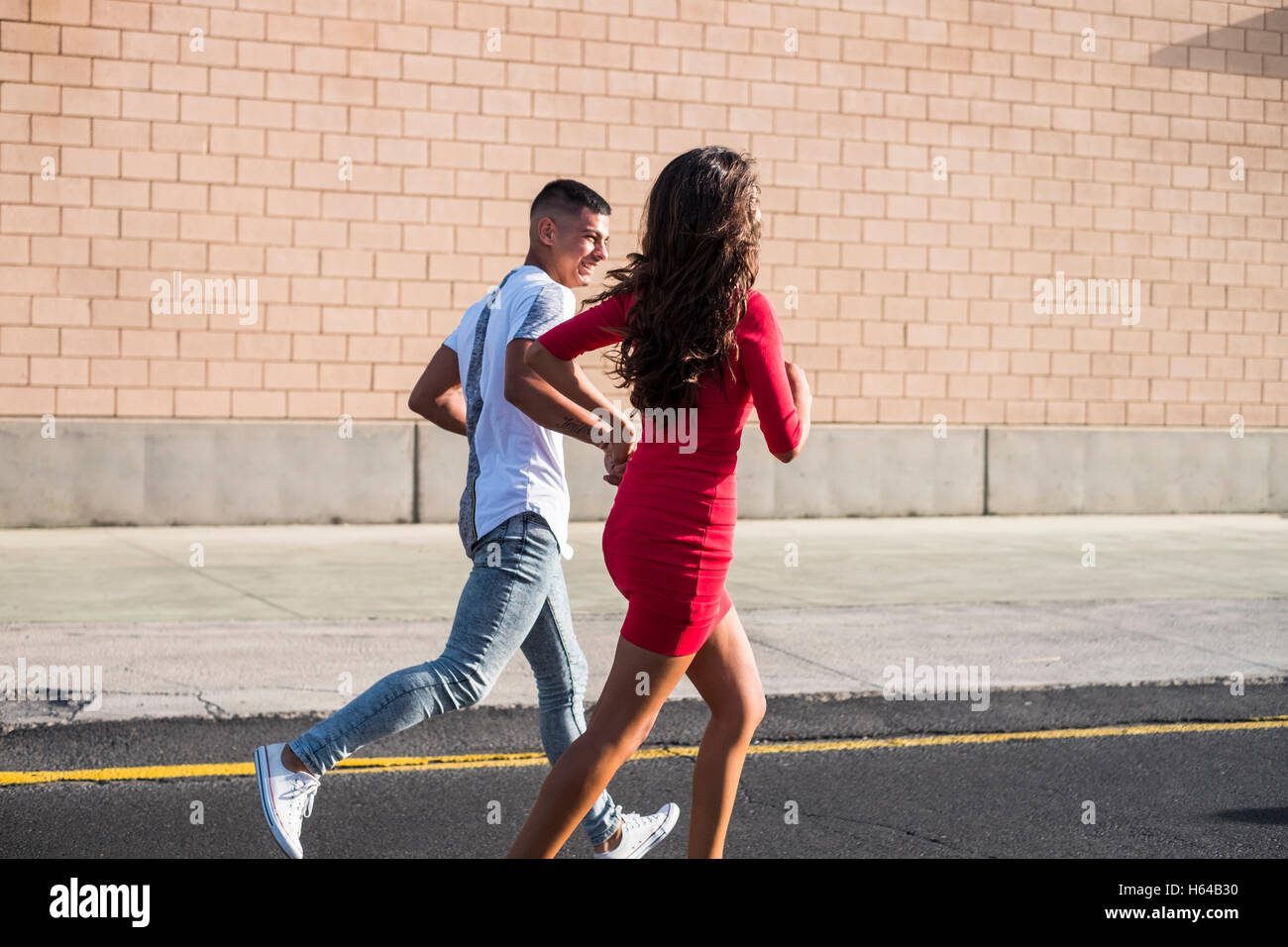 Teenage couple running hand in hand on a street Stock Photo - Alamy
