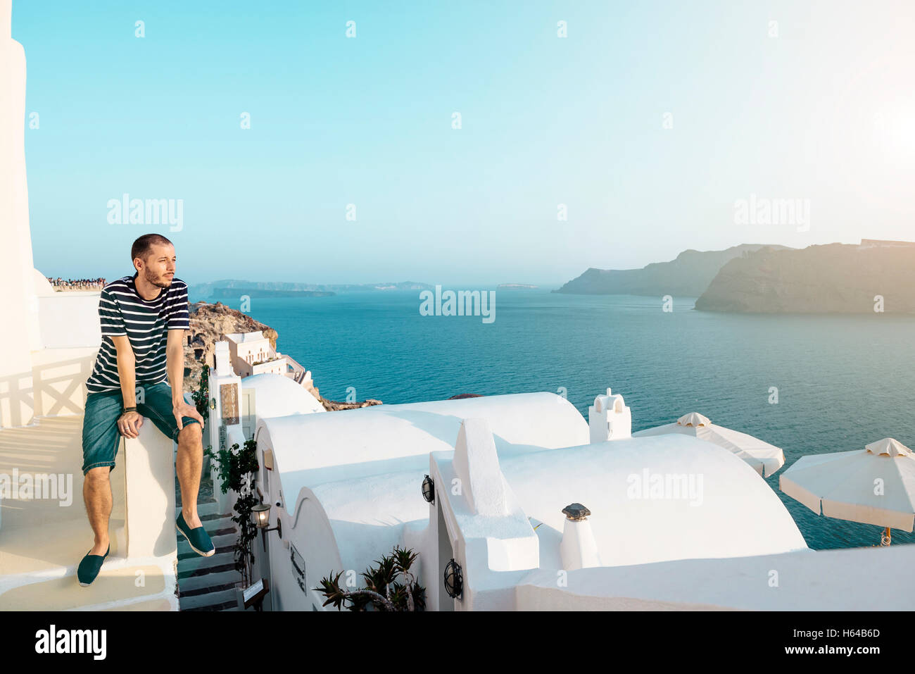 Greece, Santorini, Oia, man sitting on a wall enjoying sunset Stock ...