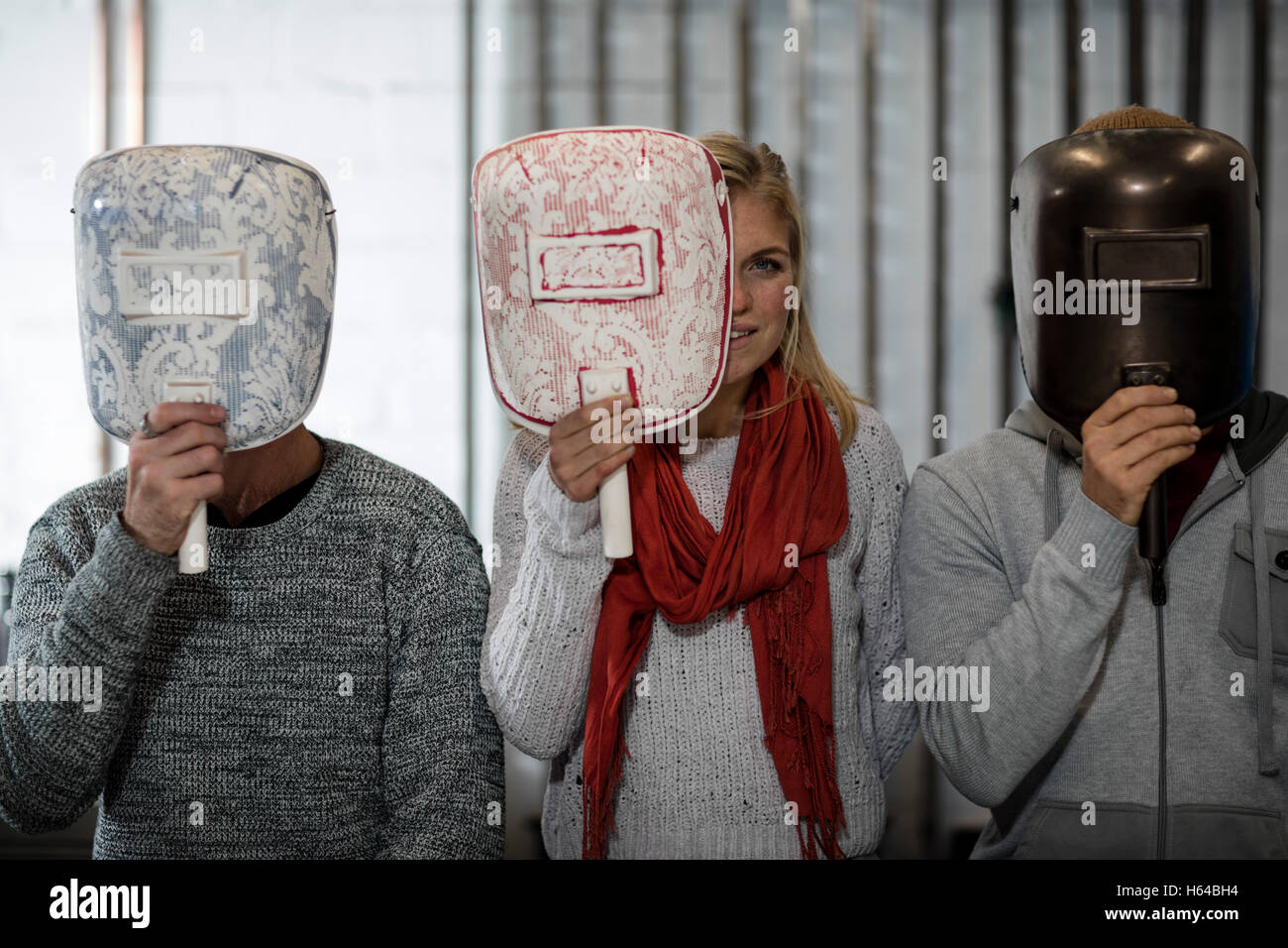 Three people hiding behind designer masks Stock Photo - Alamy