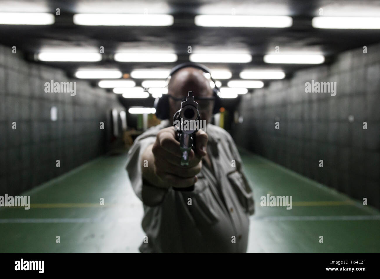 Man aiming with a revolver in an indoor shooting range Stock Photo - Alamy