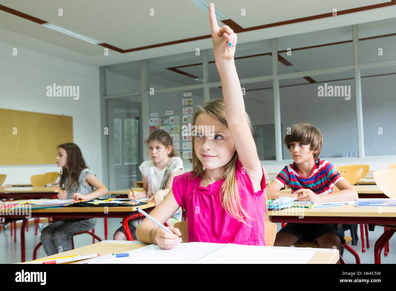 Smiling schoolgirl raising her hand Stock Photo - Alamy