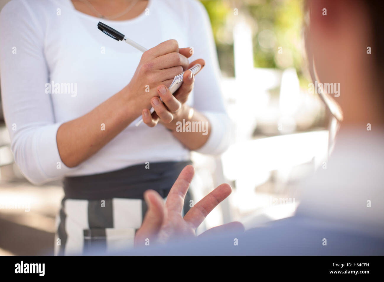 Waitress writing ordering on notepad, partial view Stock Photo - Alamy