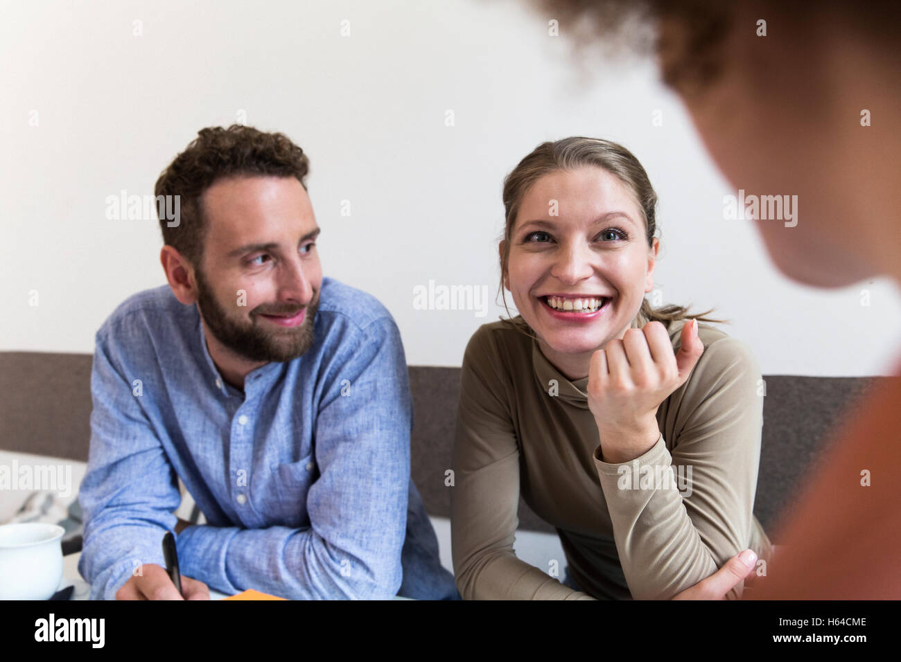 Three smiling friends sitting together Stock Photo - Alamy