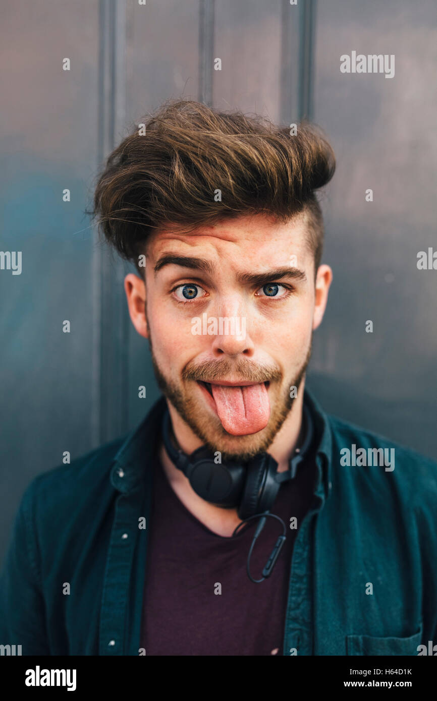Portrait of young man sticking out tongue Stock Photo - Alamy