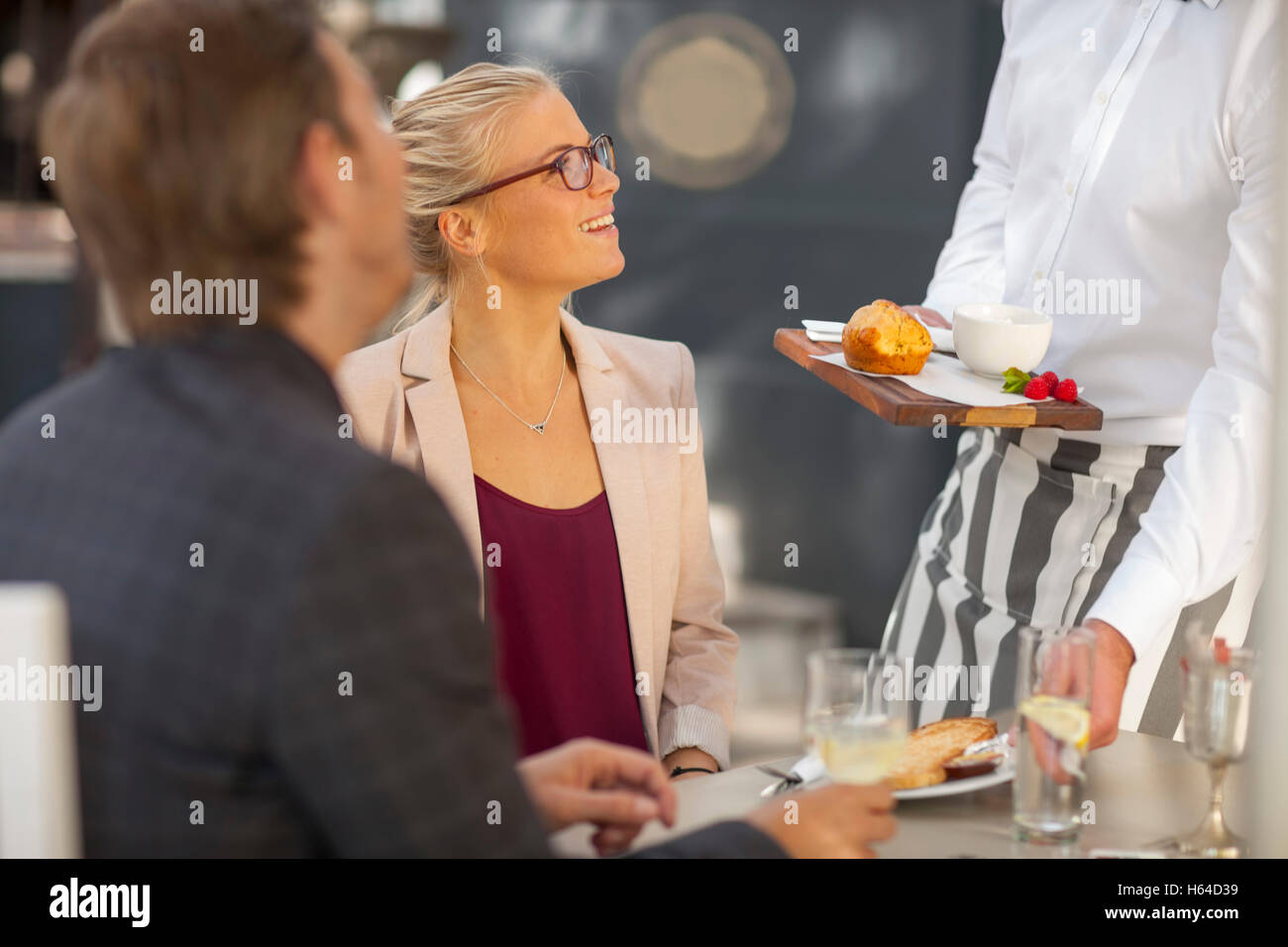 Waiter serving food at table for two Stock Photo - Alamy