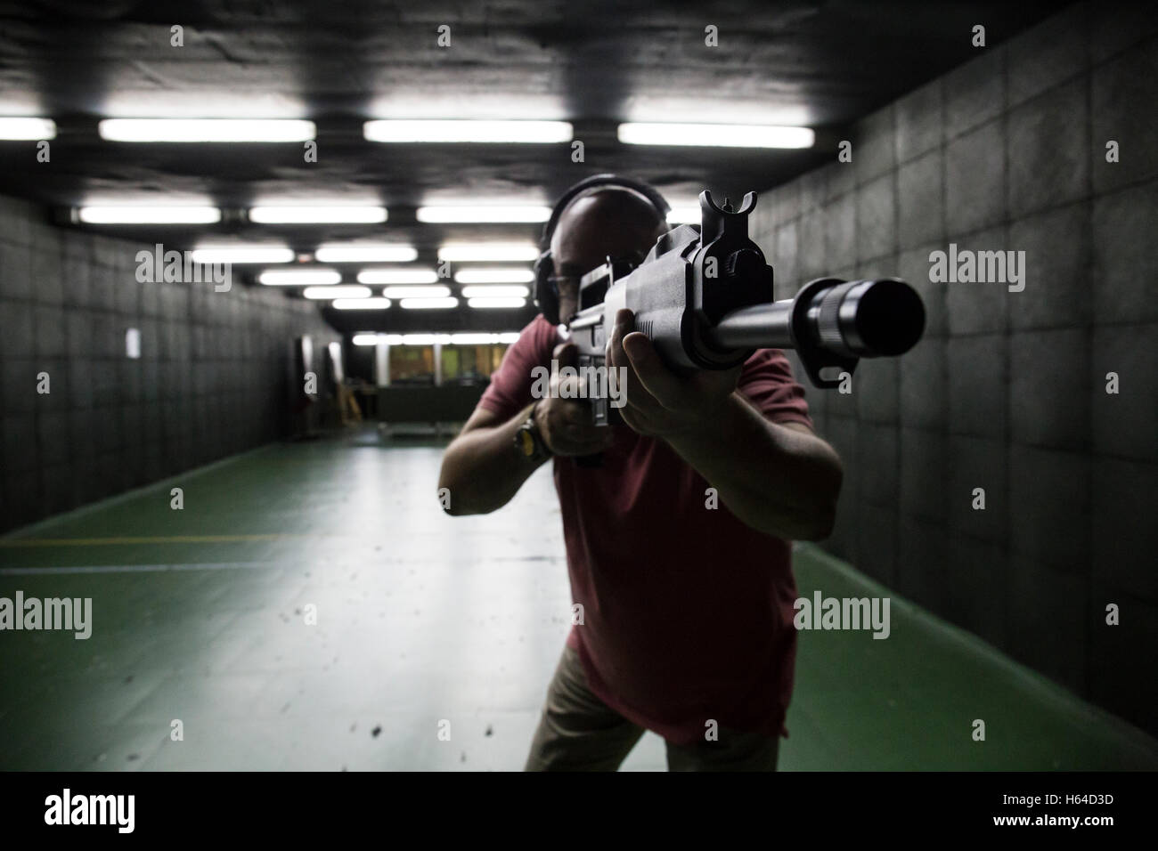 Man aiming with a tactical weapon in an indoor shooting range Stock ...