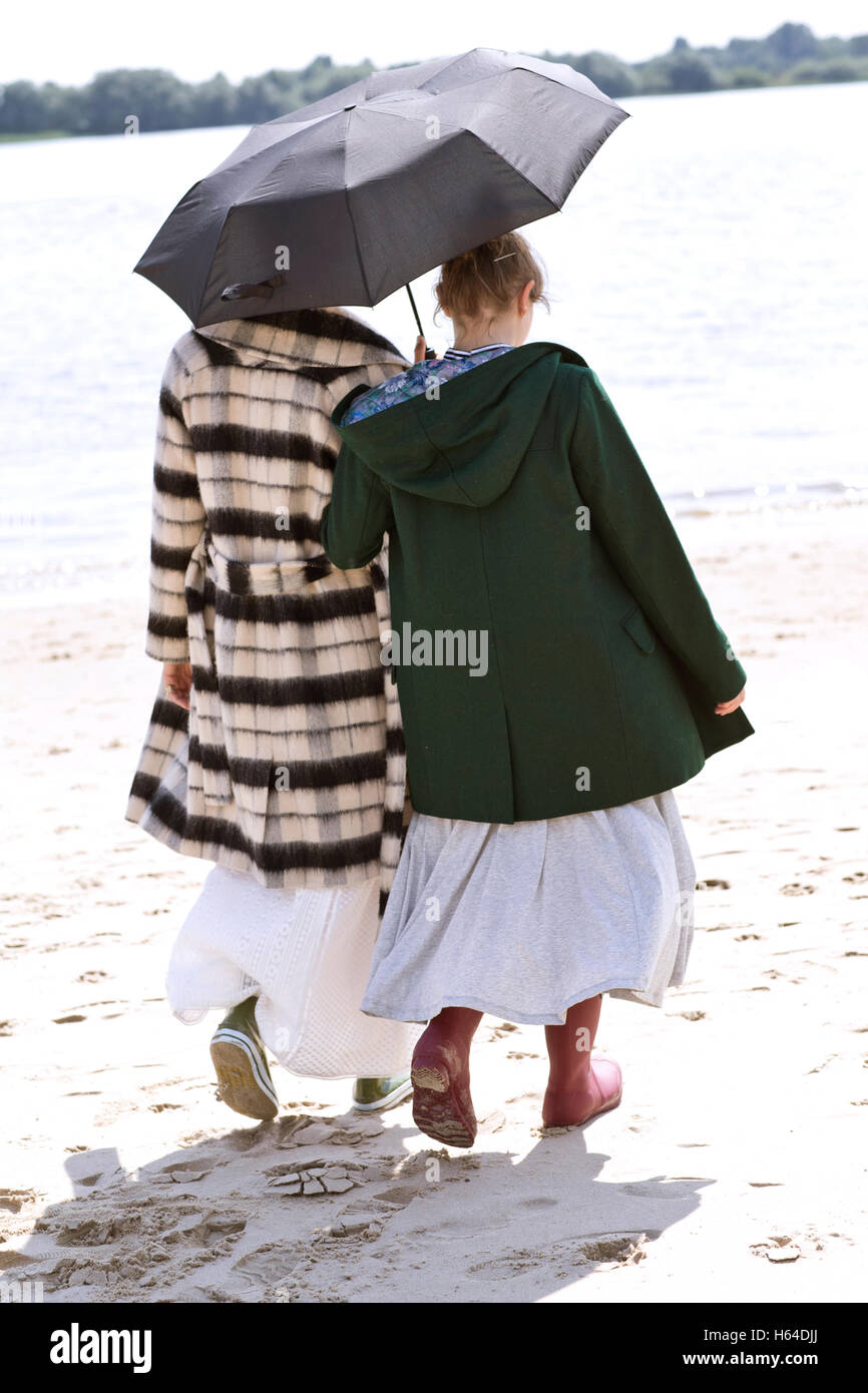Back view of two friends walking side by side on the beach with an ...
