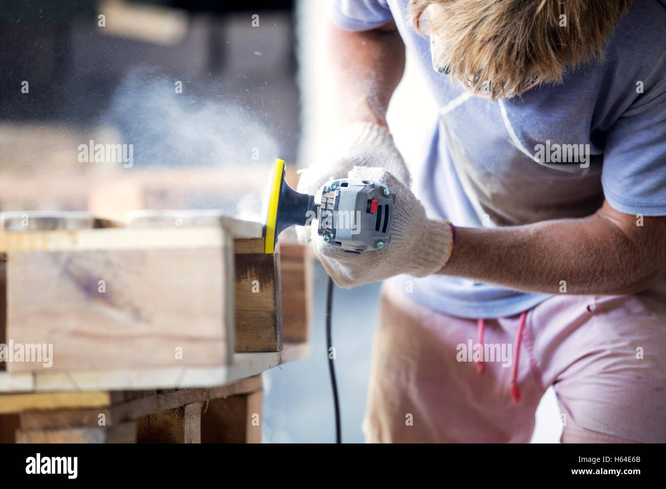 Man sanding pallet with a random orbital sander Stock Photo - Alamy