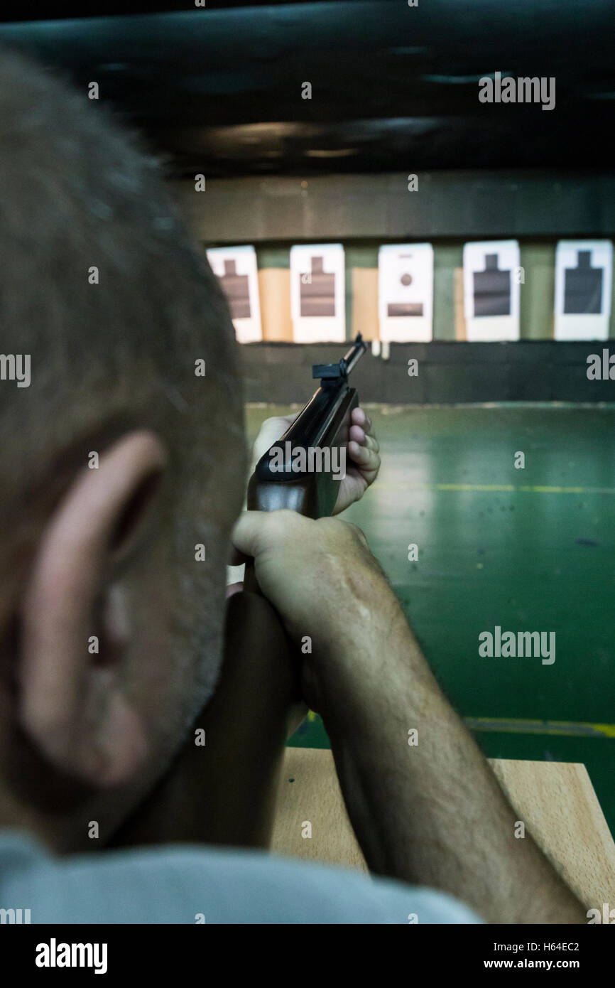 Man aiming and calibrating a carbine in an indoor shooting range Stock ...