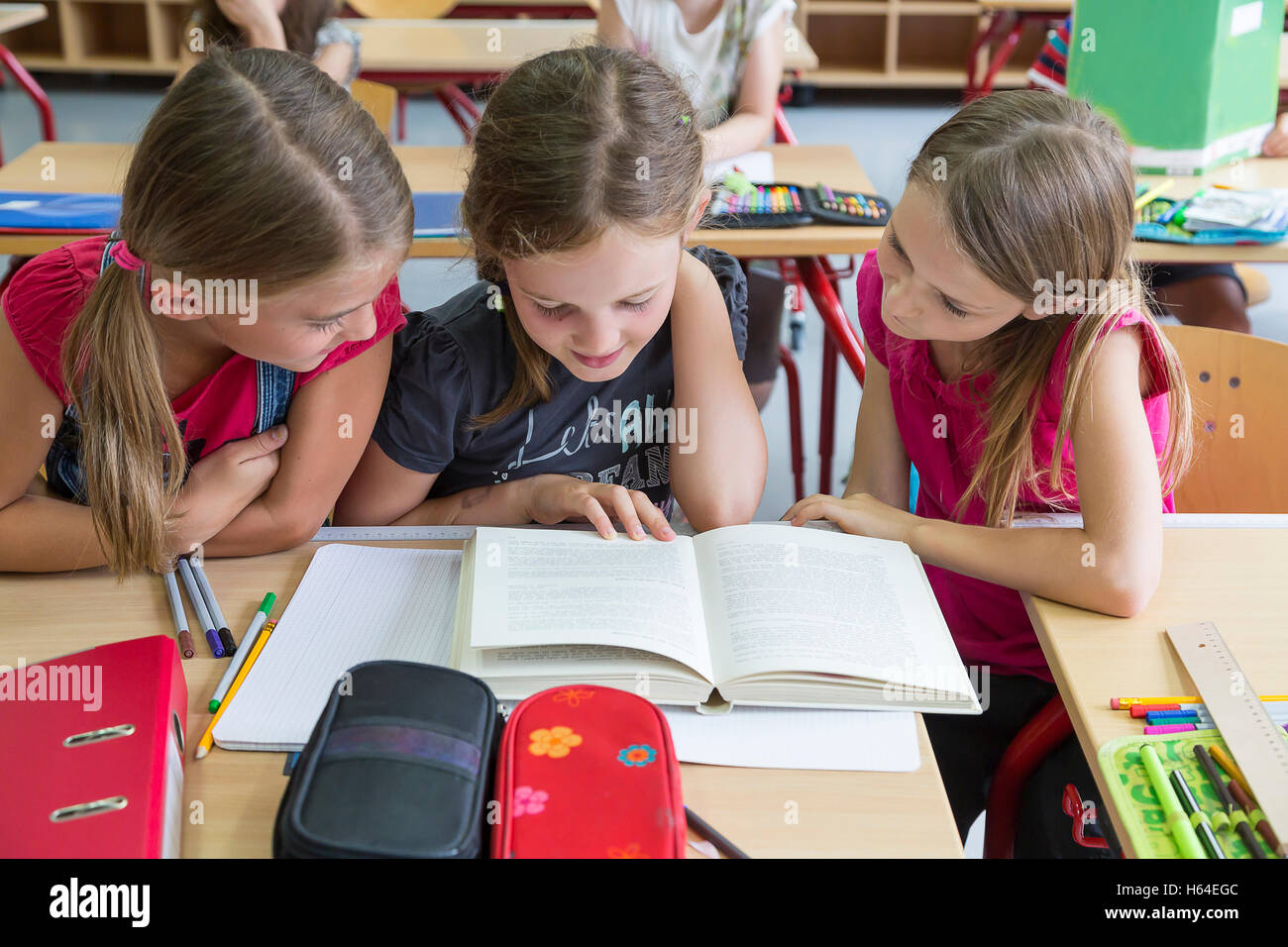 Three schoolgirls reading a book Stock Photo - Alamy