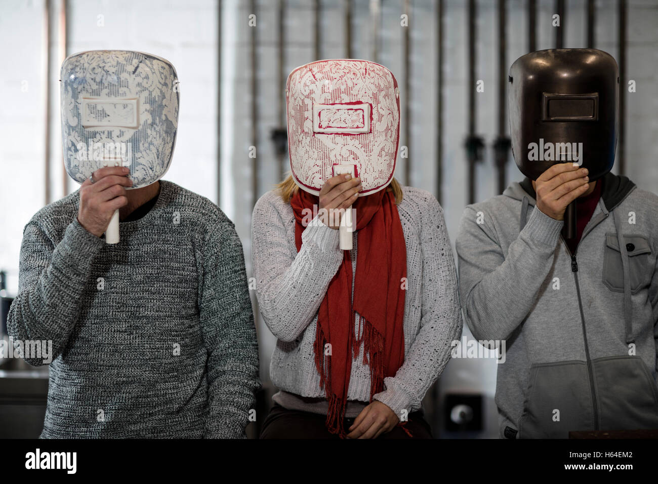 Three people hiding behind designer masks Stock Photo - Alamy