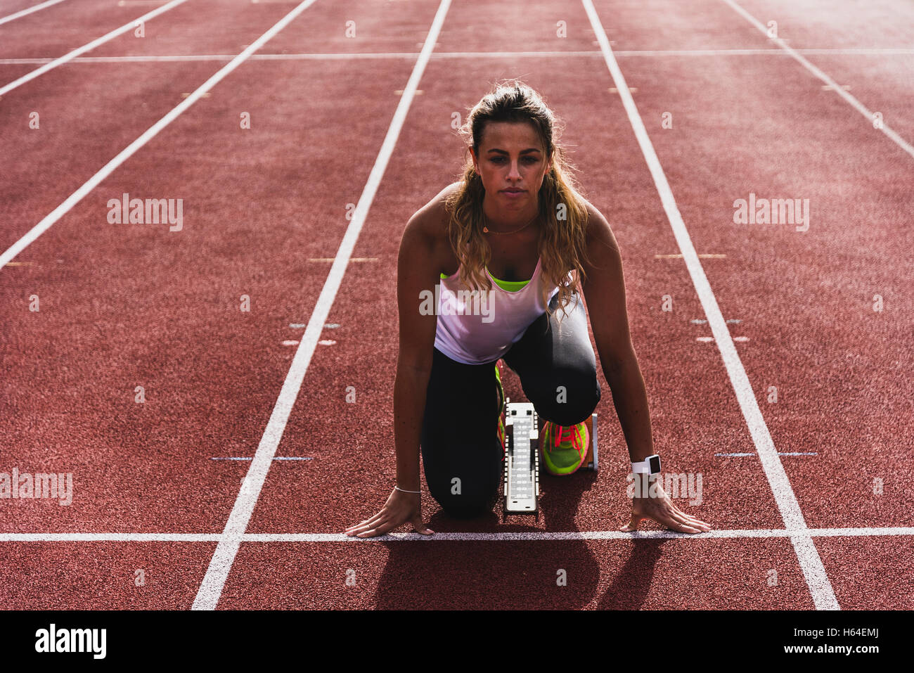 Young woman on tartan track in starting position Stock Photo - Alamy