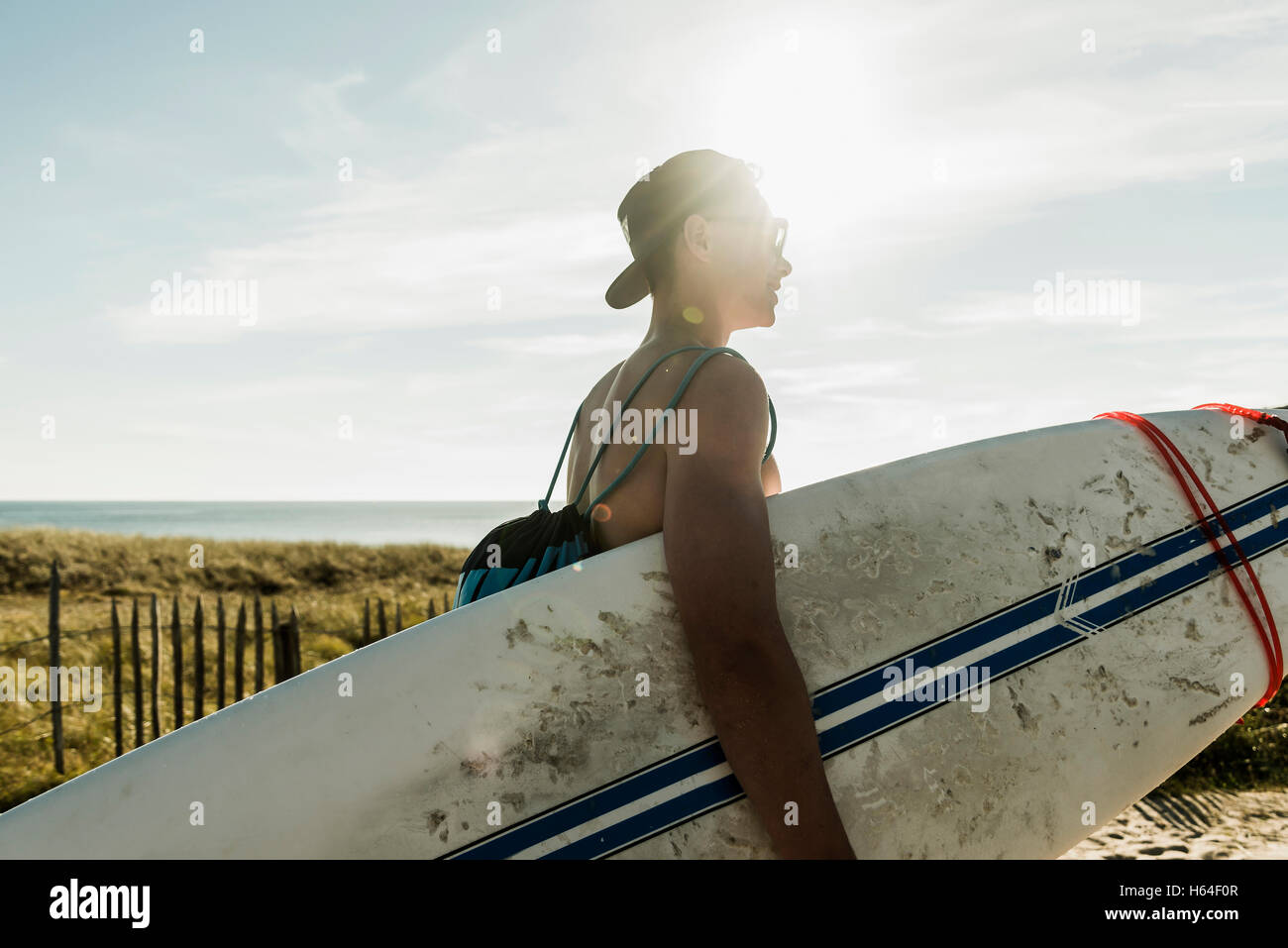 Young man carrying surfboard at the coast Stock Photo - Alamy
