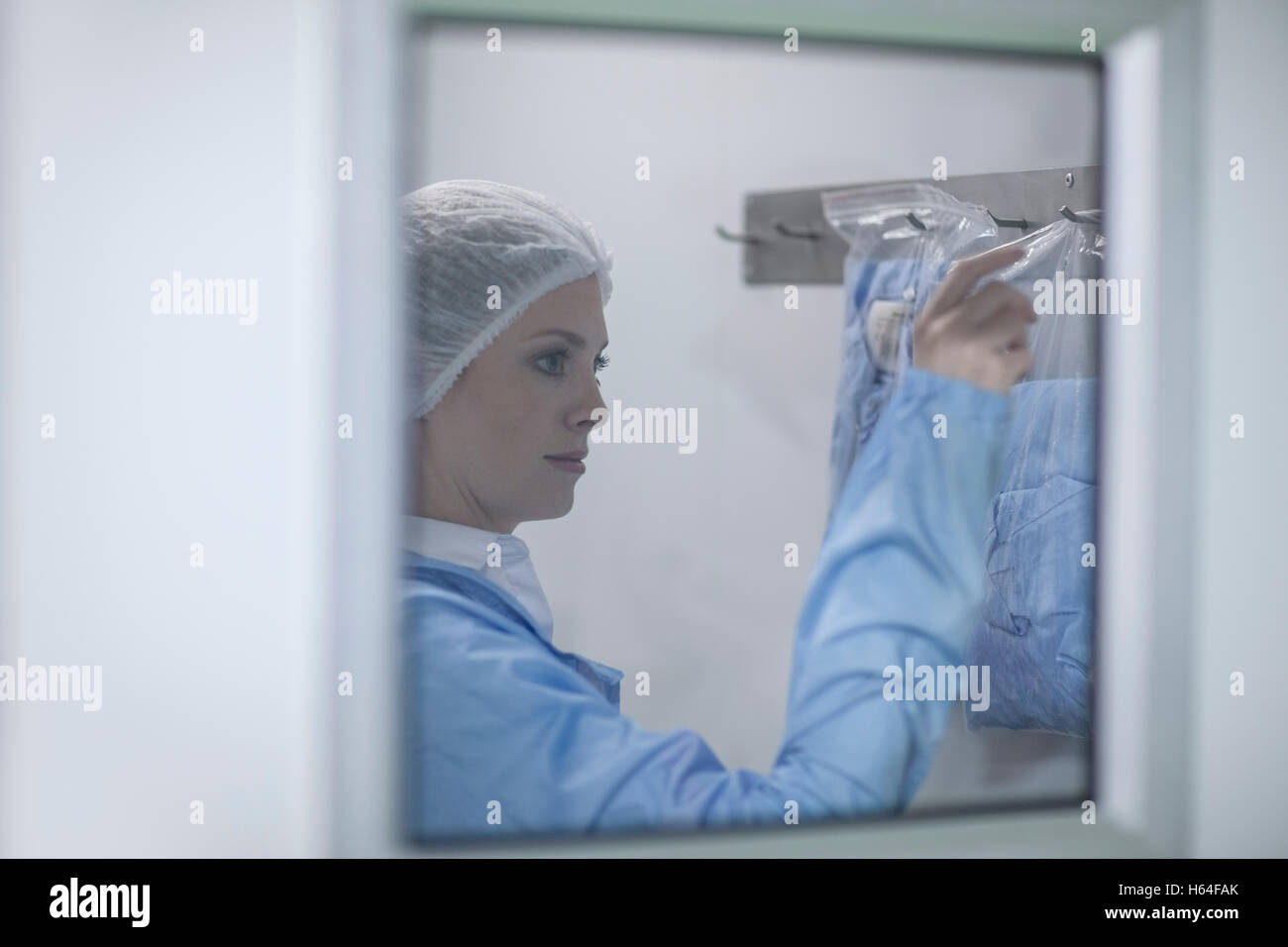 Woman behind glass pane putting on sterile protective clothing Stock ...