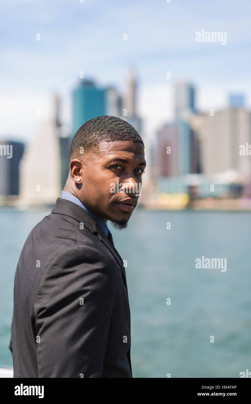 USA, Brooklyn, portrait of businessman in front of Manhattan skyline ...