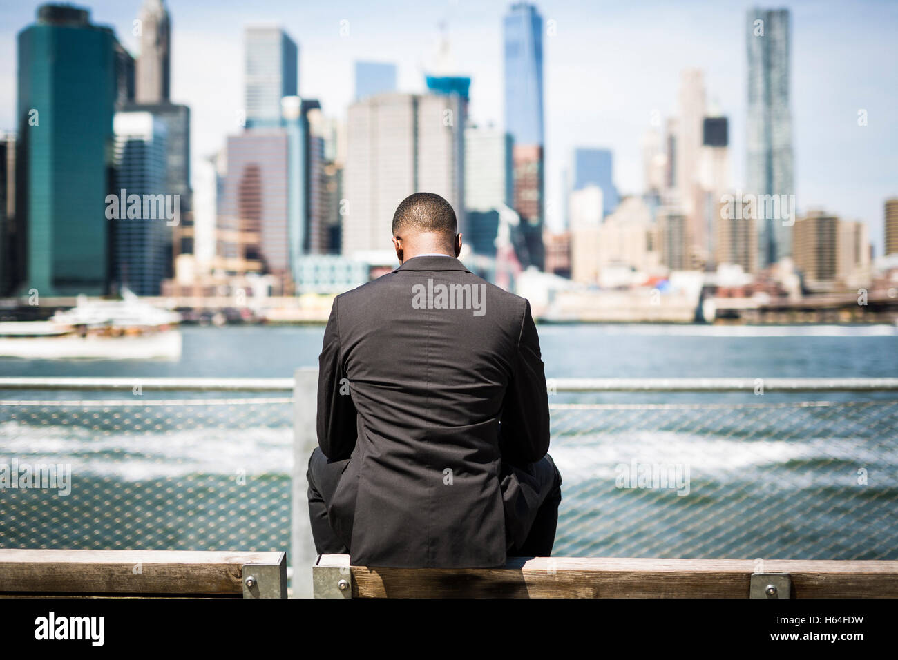 USA, Brooklyn, back view of businessman sitting on bench in front of ...