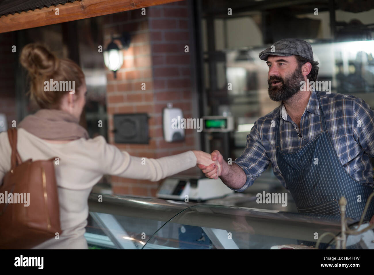 Butcher shaking hands with client in butchery Stock Photo - Alamy