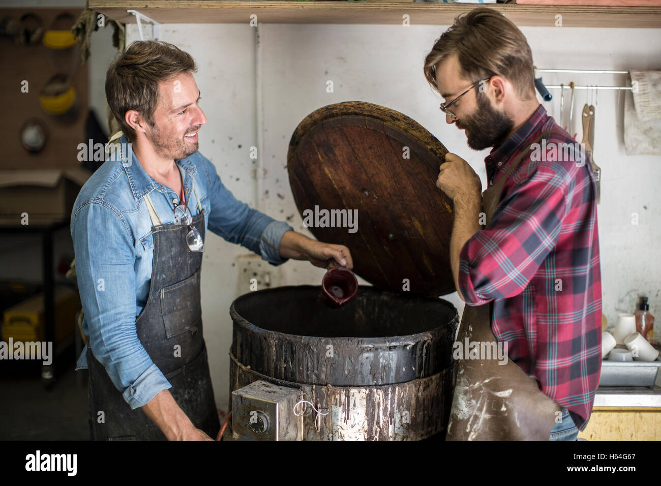 Two men in workshop looking in barrel Stock Photo - Alamy