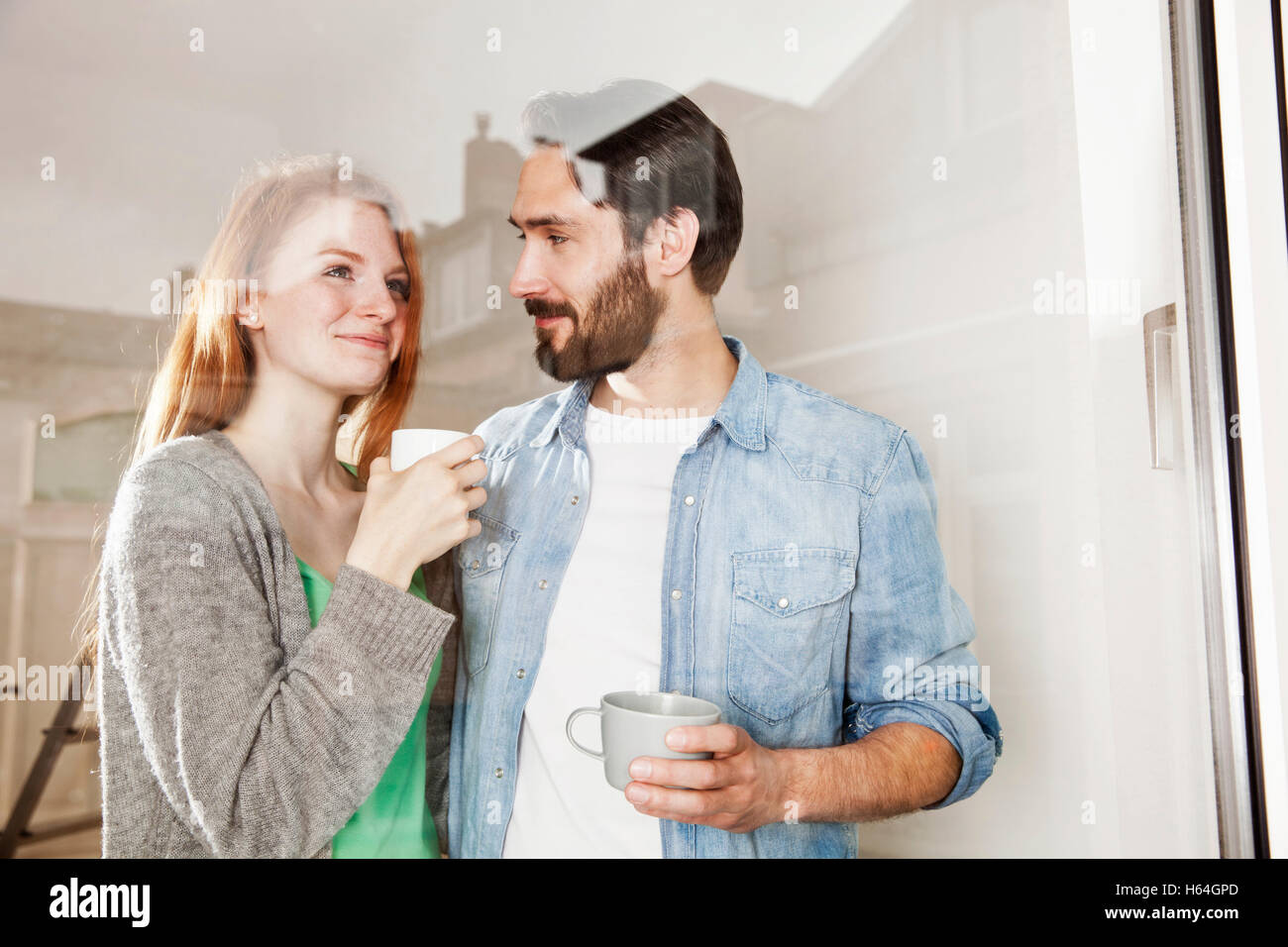 Smiling young couple having a coffee break behind windowpane Stock ...