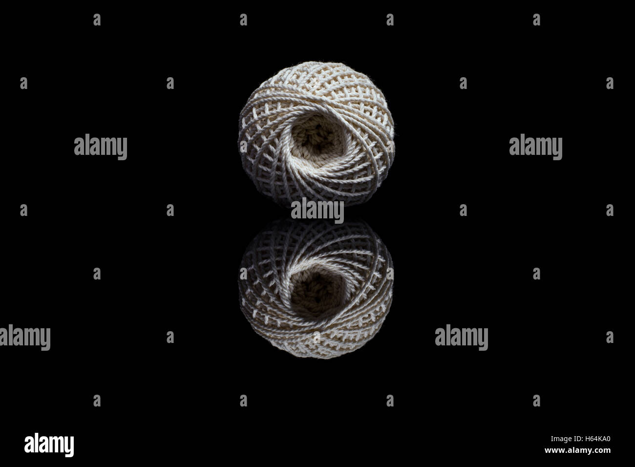 Front view of white ball of string isolated on black reflective ...