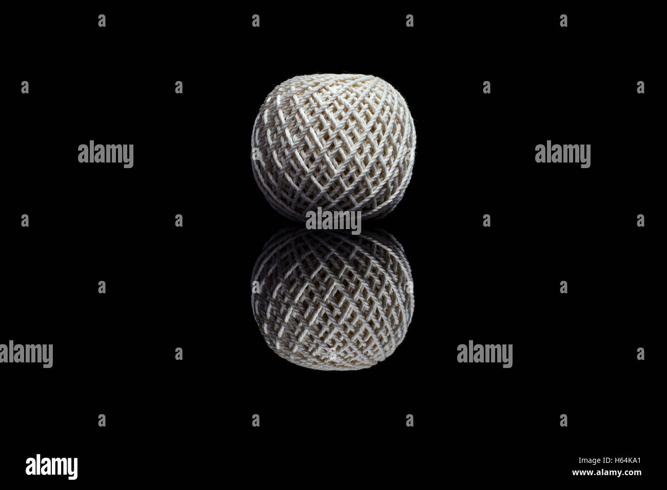 Side view of white ball of string isolated on black reflective ...