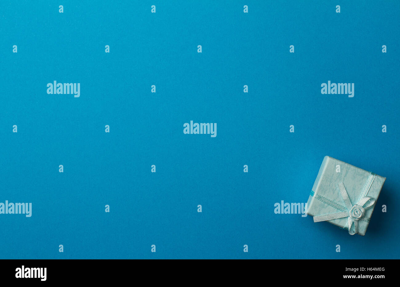 Top view of light blue background with small gift box with ribbon for ...