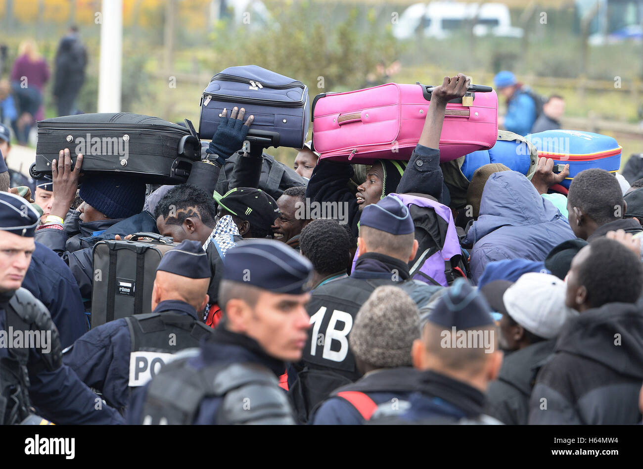 A group of men with suitcases in a large queue of migrants outside a ...