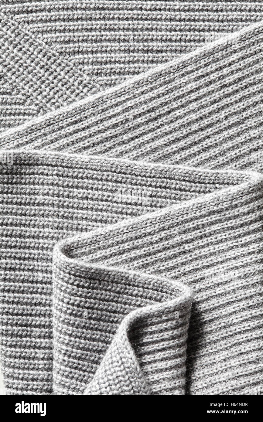 A full page close up of grey fine knit jumper fabric texture with folds ...