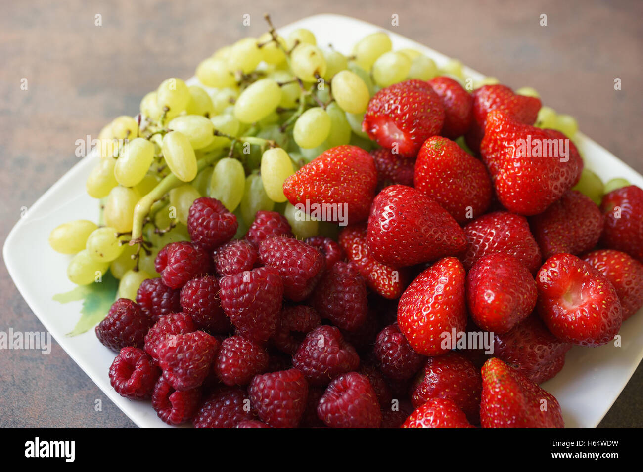 Plate with mix of strawberries, raspberries and grapes, top view ...