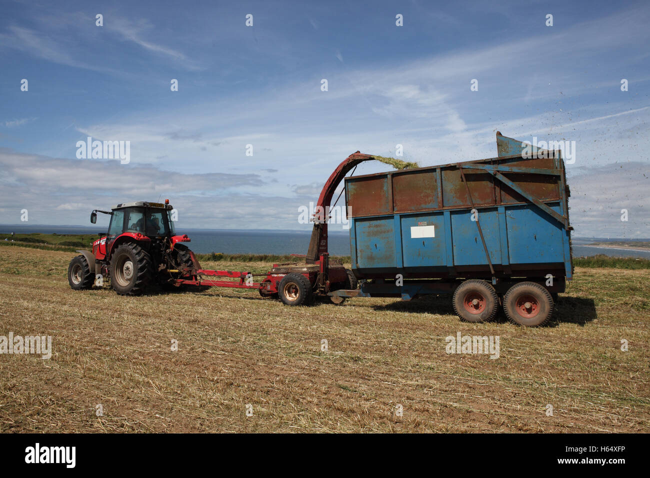 View of a tractor pulling a combine gathering hay and collecting it ...