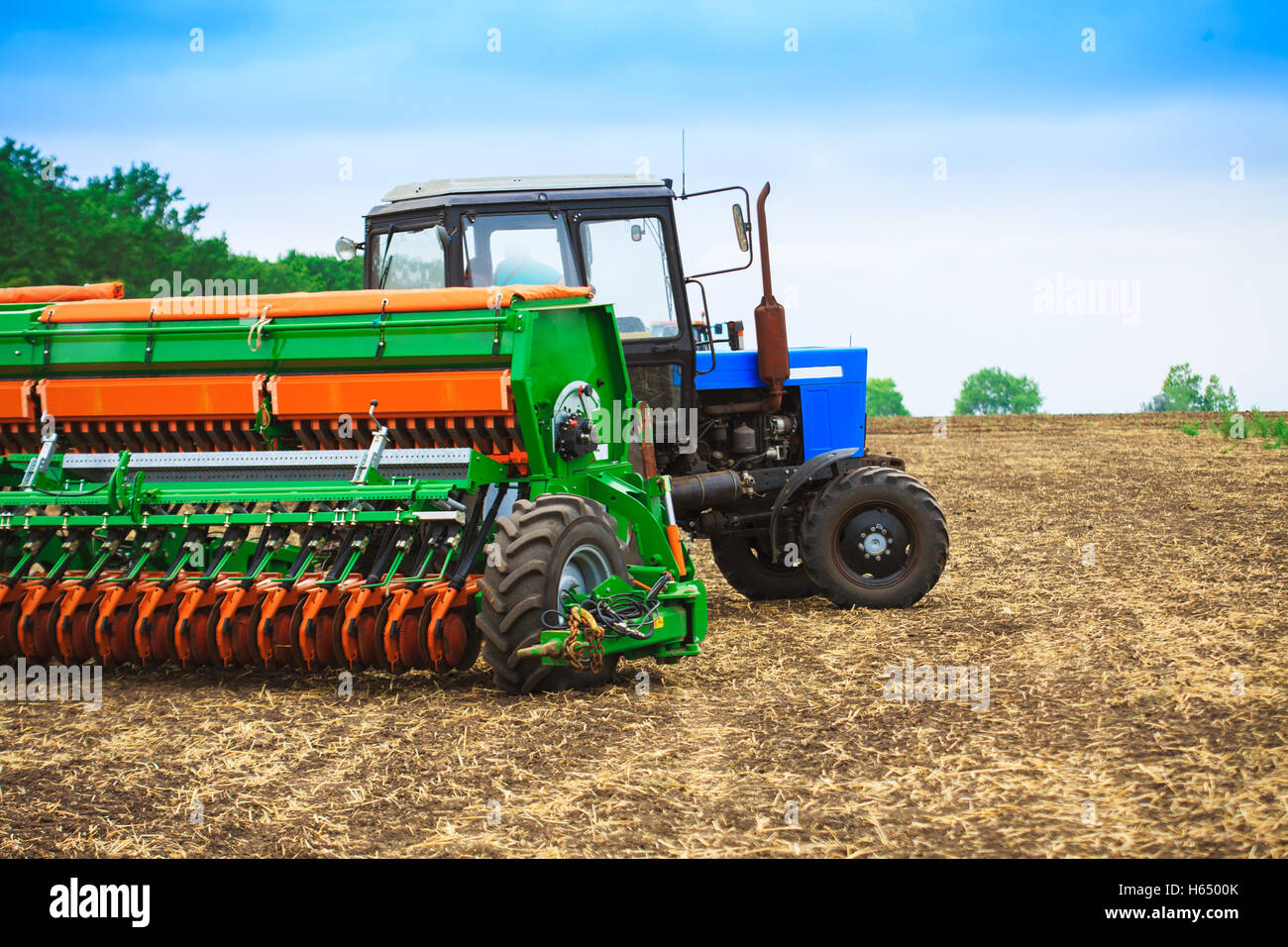Tractor with a harrow to work the land field Stock Photo - Alamy