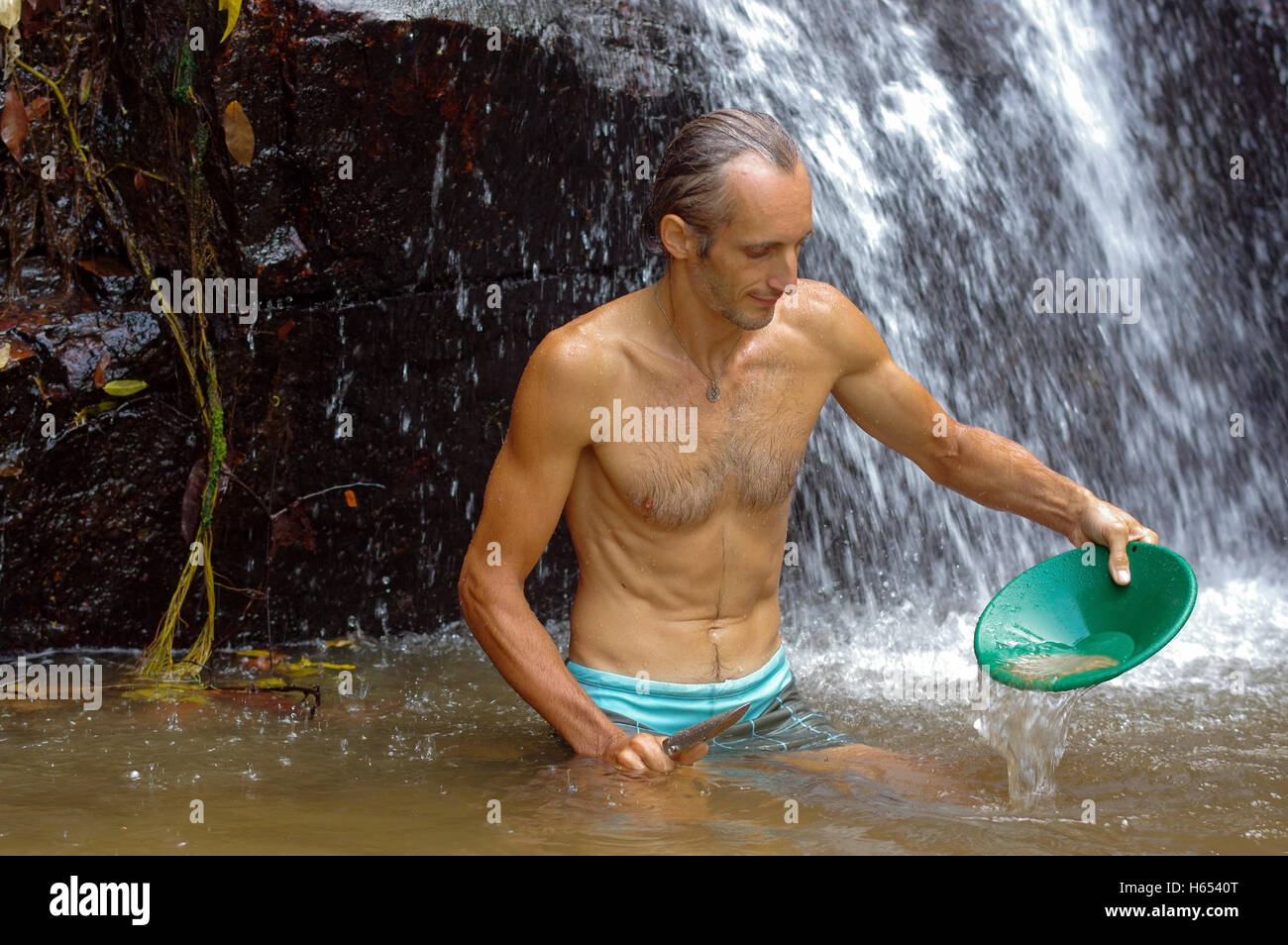 a man gold panning in a river with a sluice box Stock Photo - Alamy